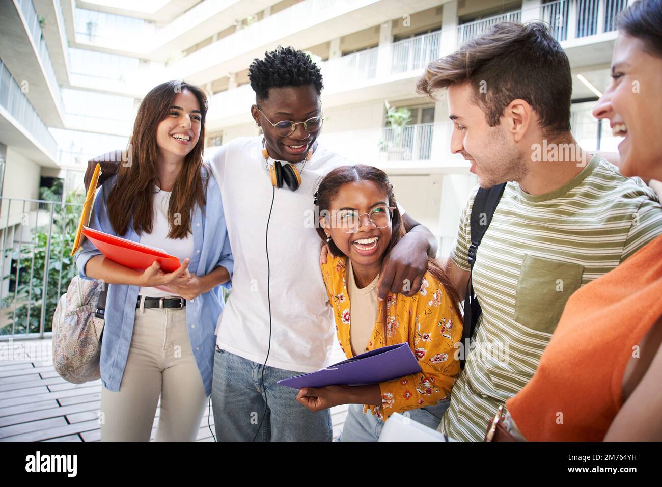A group of cheerful students laugh on campus, leaving their classes ...