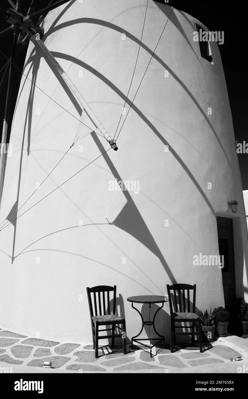 Greek windmill on an island of Cyclades in Greece with two chairs and a ...