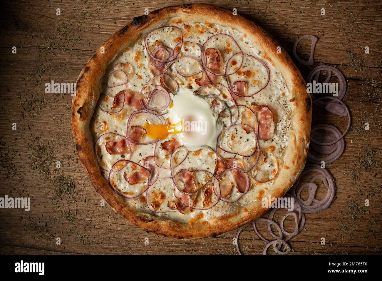 delicious pizza with ham, onions and fried eggs in the middle. top view ...