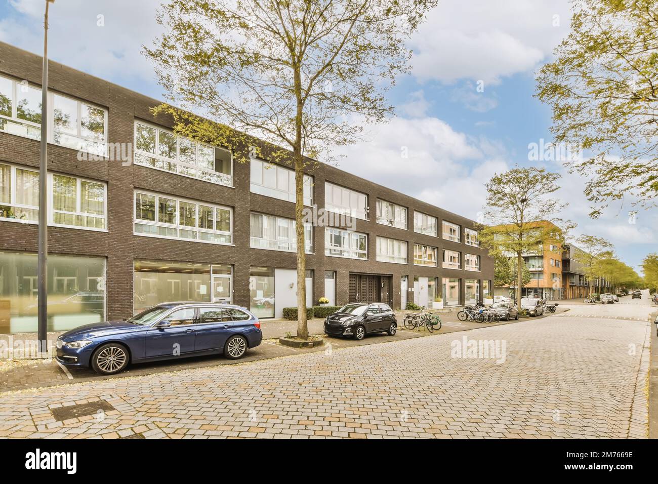 a city street with cars parked on the side and buildings in the back ...