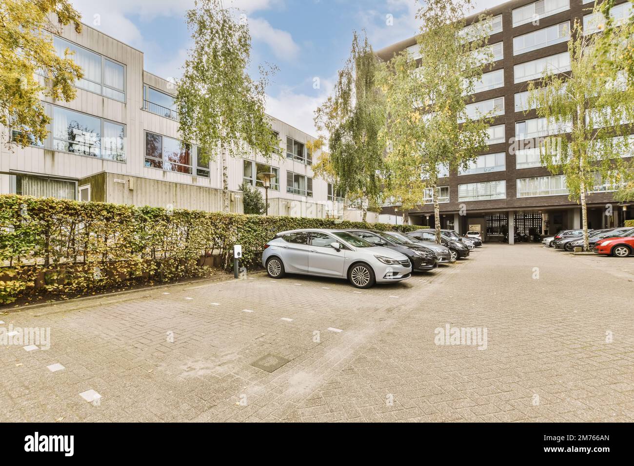 some cars parked in front of an office building with trees and bushes ...