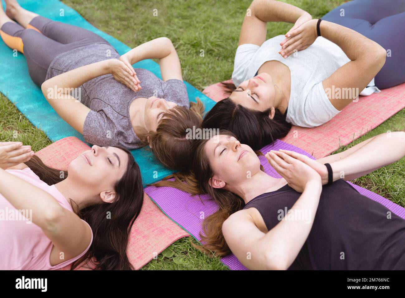 Group of caucasian female friends practicing yoga outdoors. They are ...