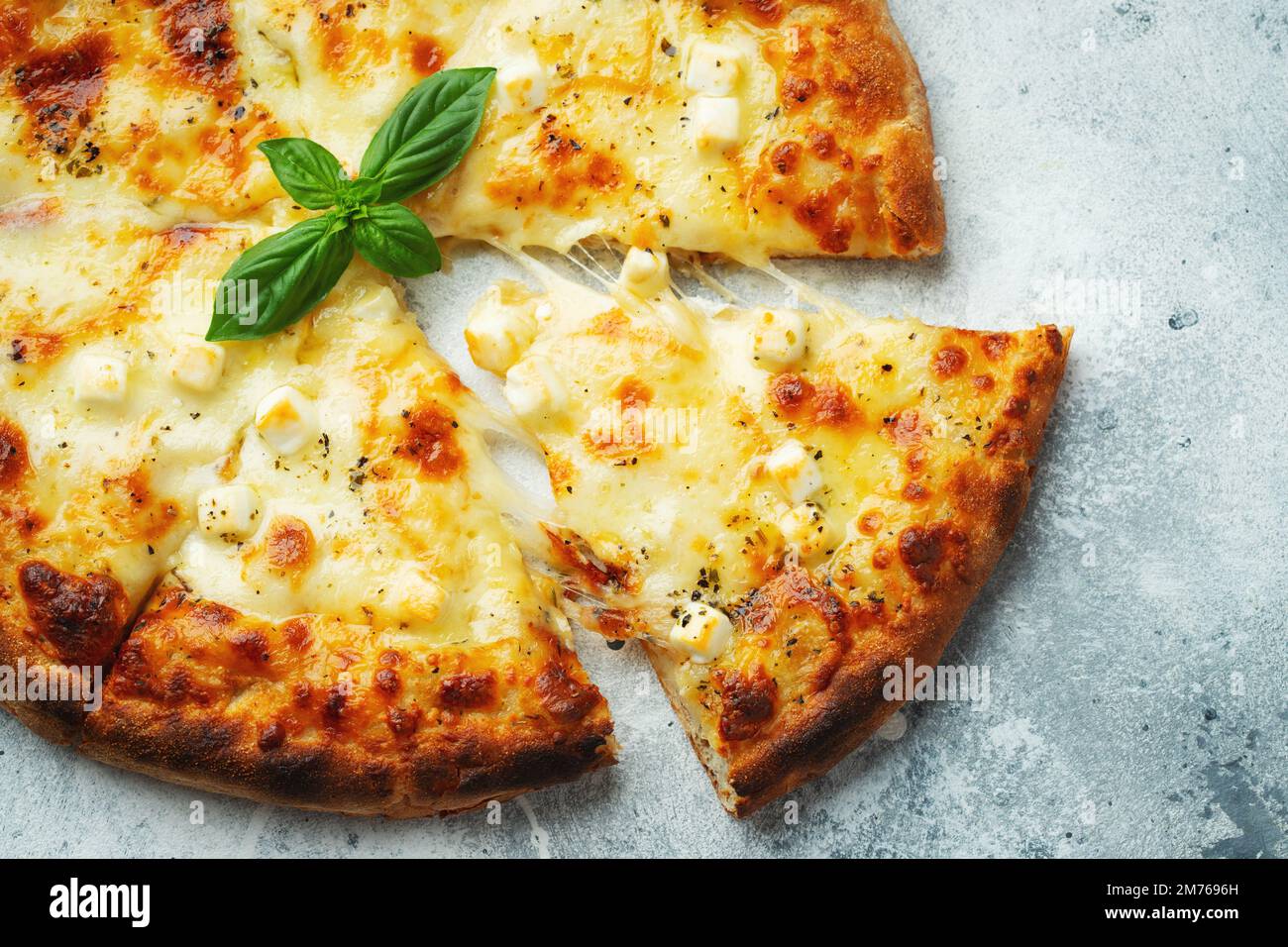Italian pizza four cheeses with stretching cheese and basil on a light ...