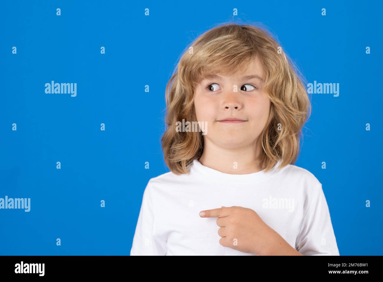 Kid boy looking away, pointing finger on isolated studio background ...
