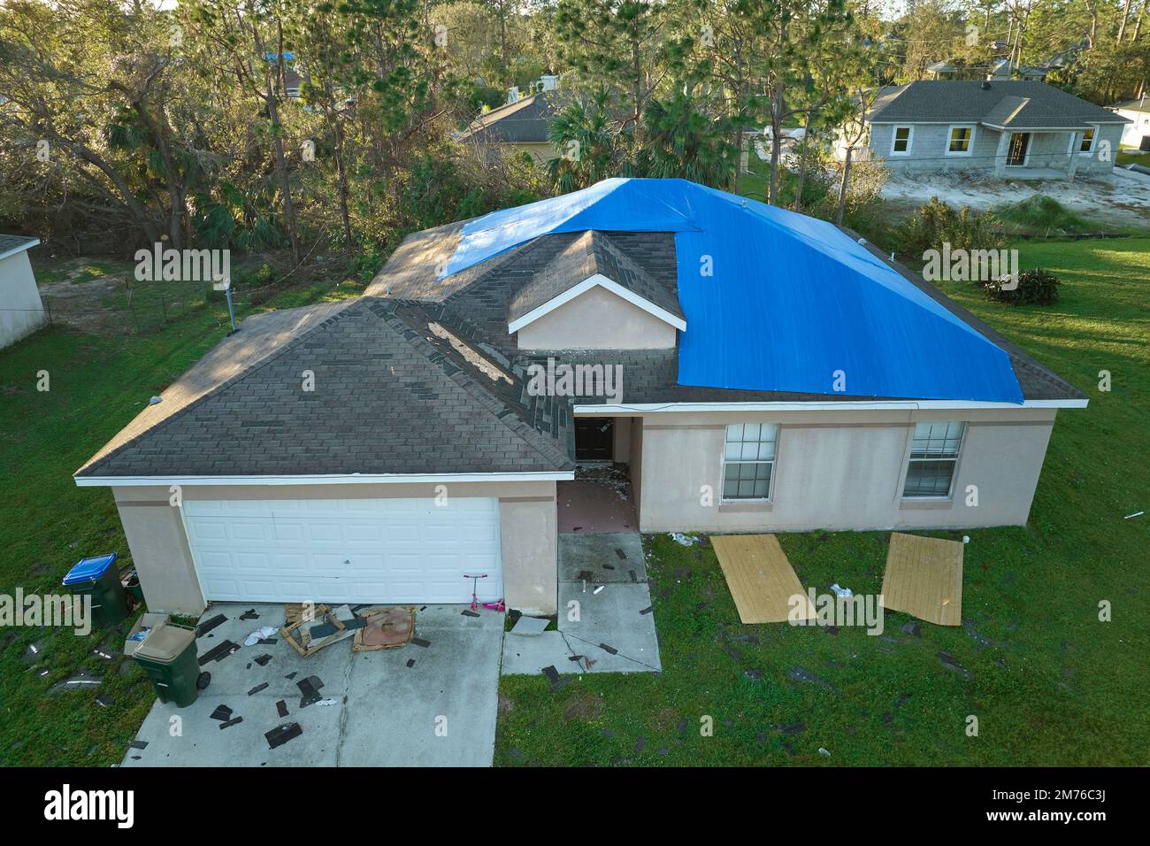 Aerial view of damaged in hurricane Ian house roof covered with blue ...