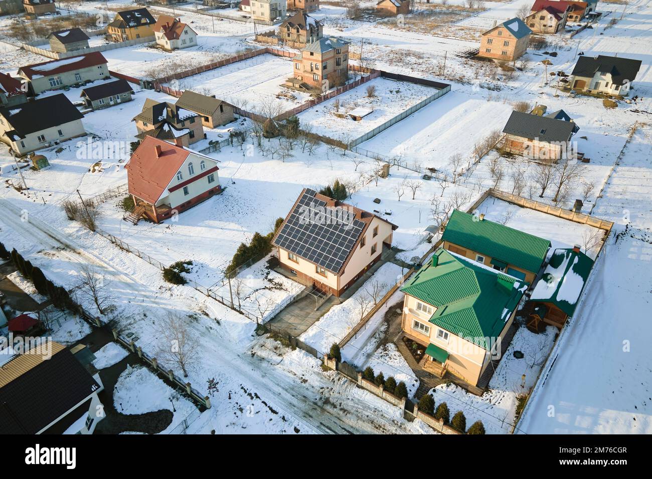 Aerial view of house roof with solar panels covered with snow melting ...
