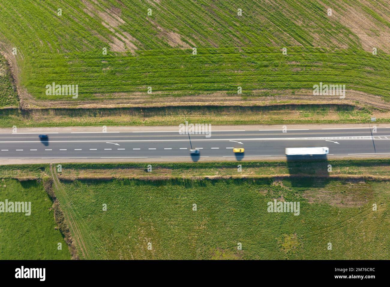 Aerial view of intercity road between green agricultural fields with ...