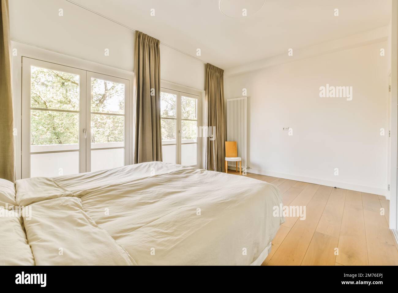 a bedroom with white walls and wood flooring the room is well lit by ...