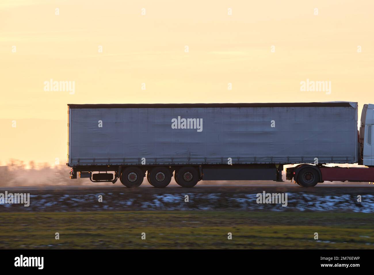 Semi-truck with cargo trailer driving on highway hauling goods in evening. Delivery ...