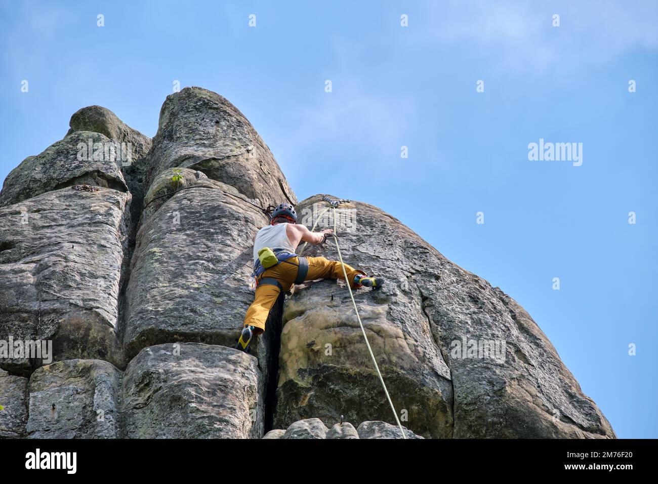 Strong male climber climbing steep wall of rocky mountain. Sportsman ...