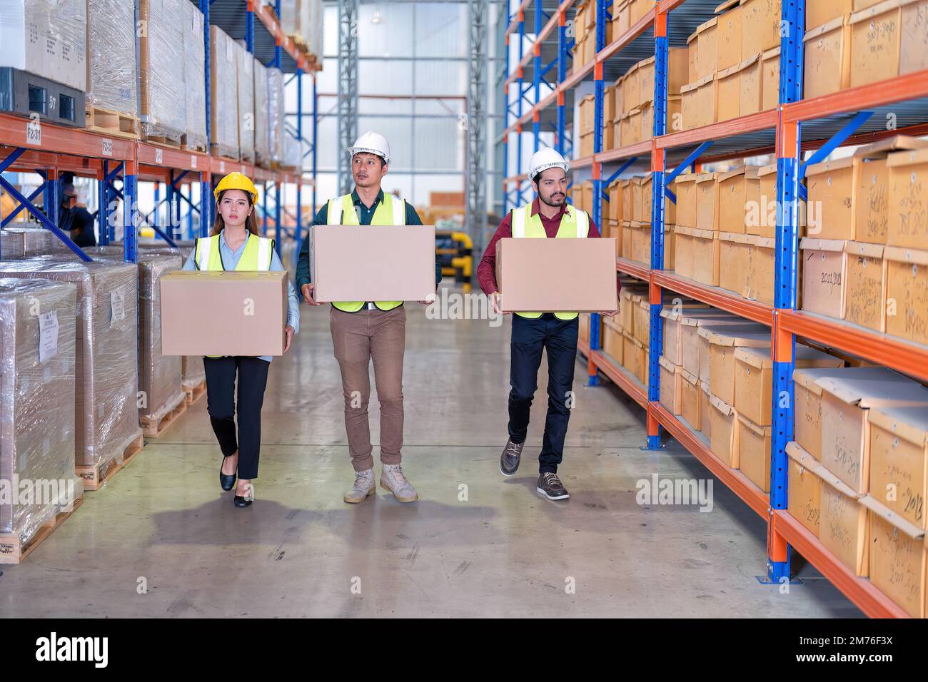 Warehouse worker hold the carton box walk along the steel racking shelf ...