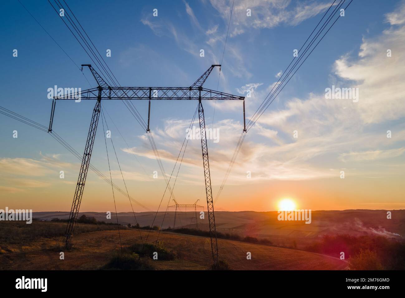 Dark silhouette of high voltage tower with electric power lines at ...