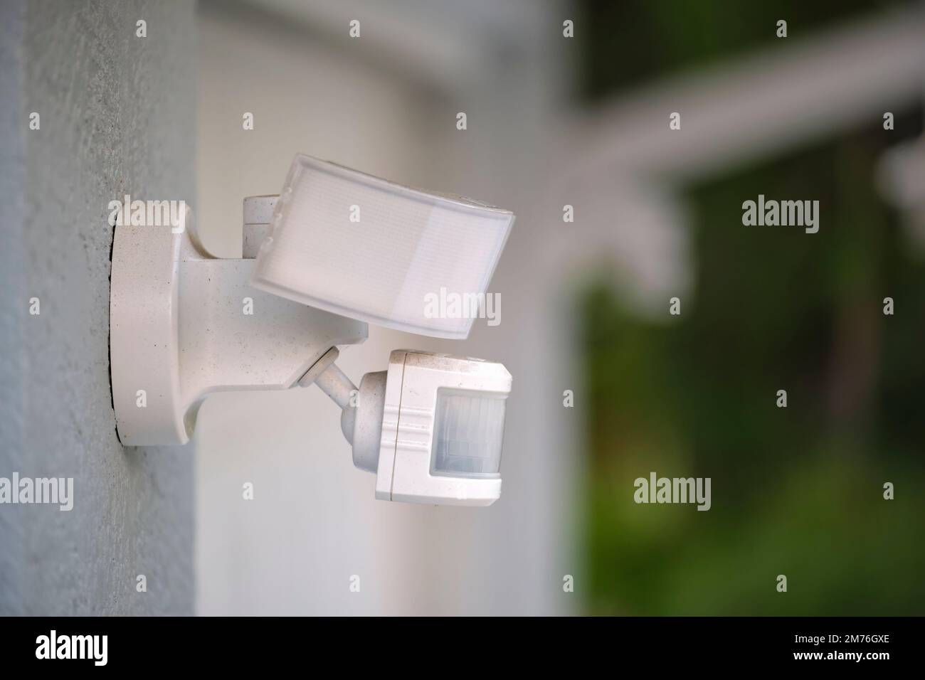 Motion sensor with light detector mounted on exterior wall of private ...