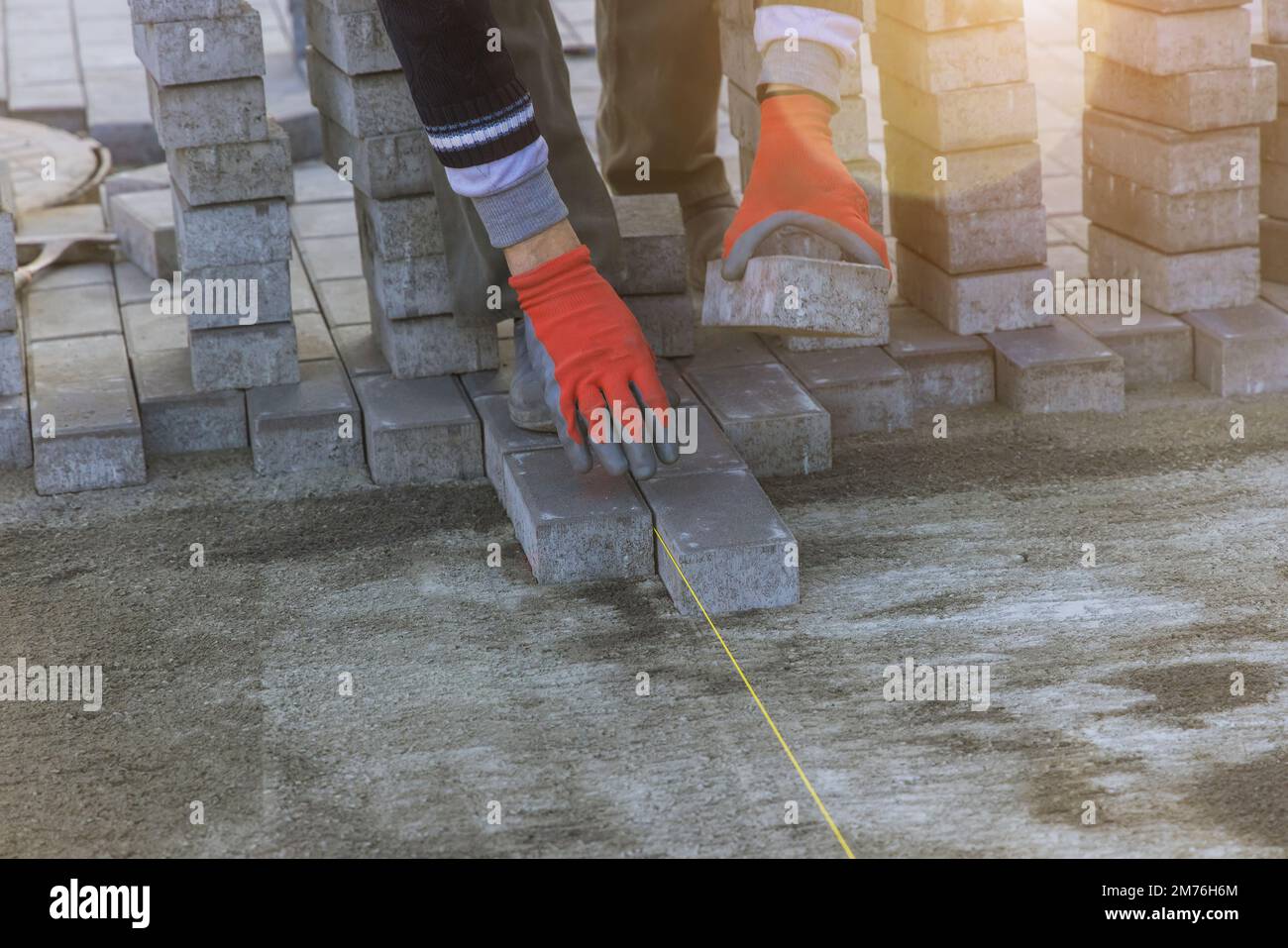 Master laying gray concrete paving brick slabs in house courtyard on ...