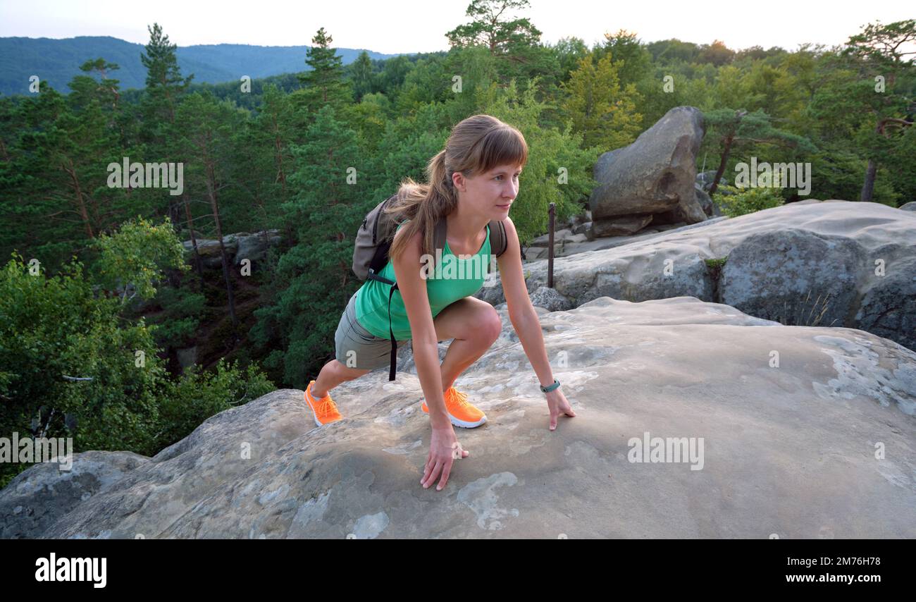 Sportive woman climbing alone on hillside rocky trail. Female hiker ...
