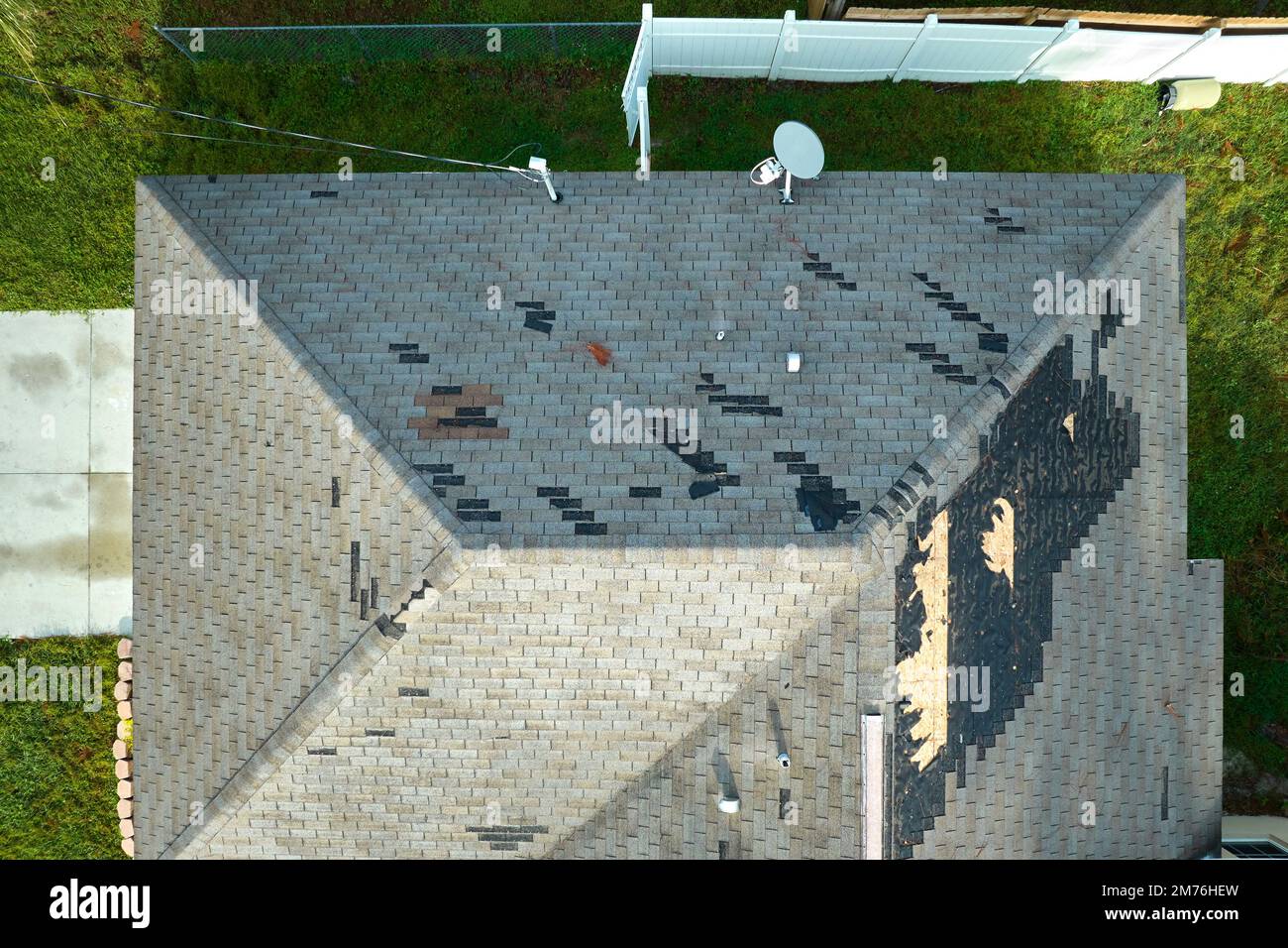 Wind damaged house roof with missing asphalt shingles after hurricane ...