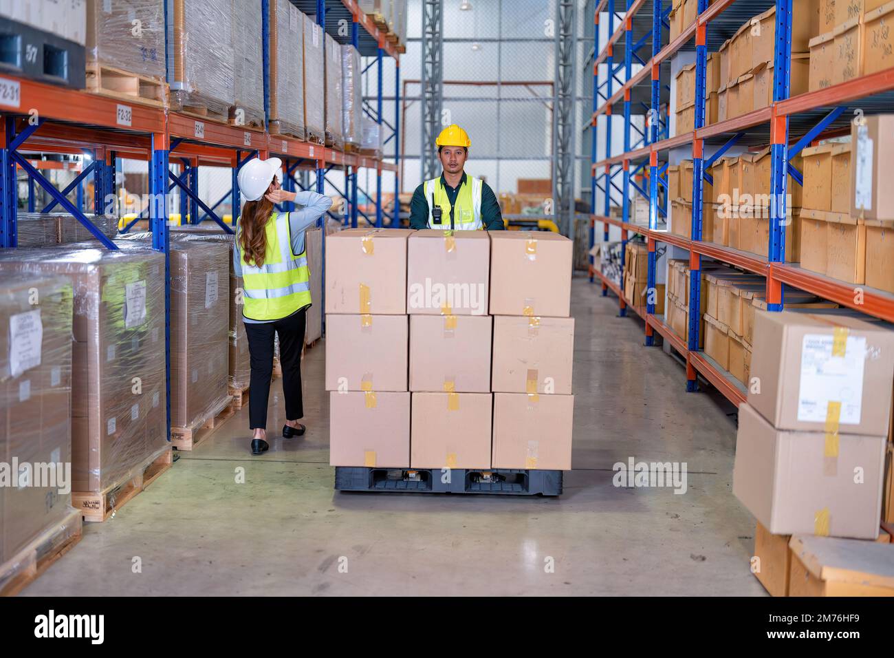 Warehouse worker pull manual pallet hand truck stack with boxes walk ...