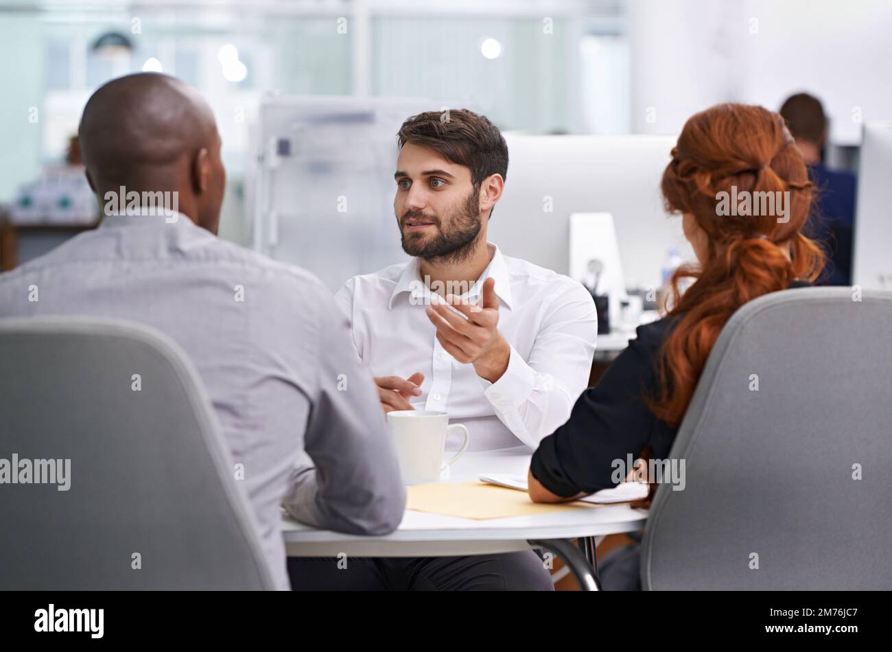 Sharing the vision with his team. Three work colleagues sitting ...