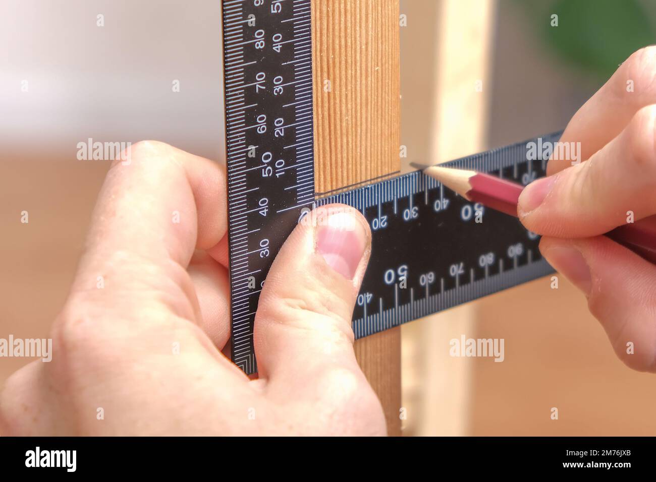 Carpenter using carpenter square to mark the line of wood cut for ...