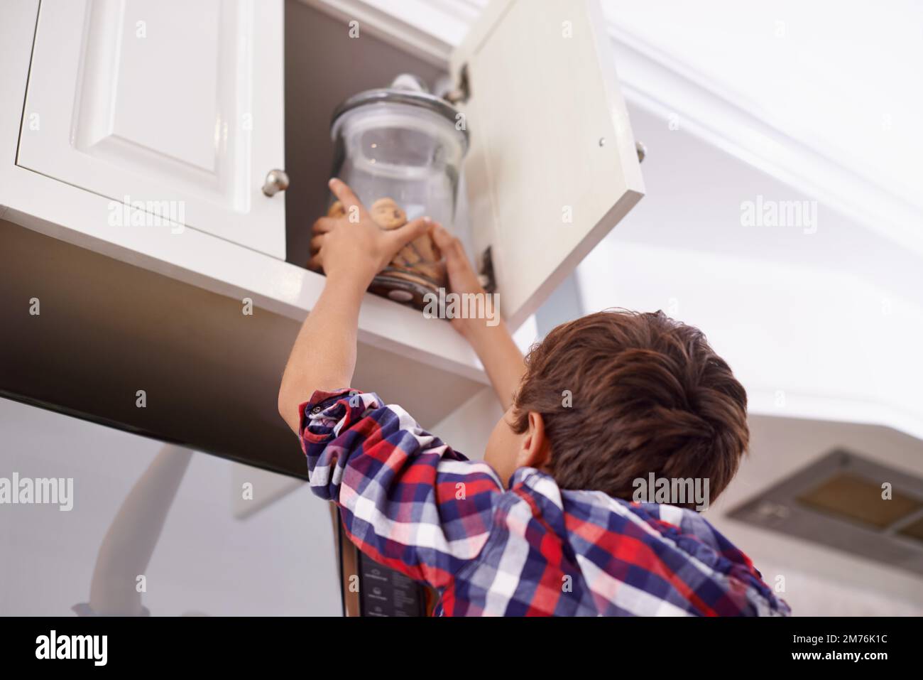 Mom will never know...A young boy reaching for a cookie jar in the top ...