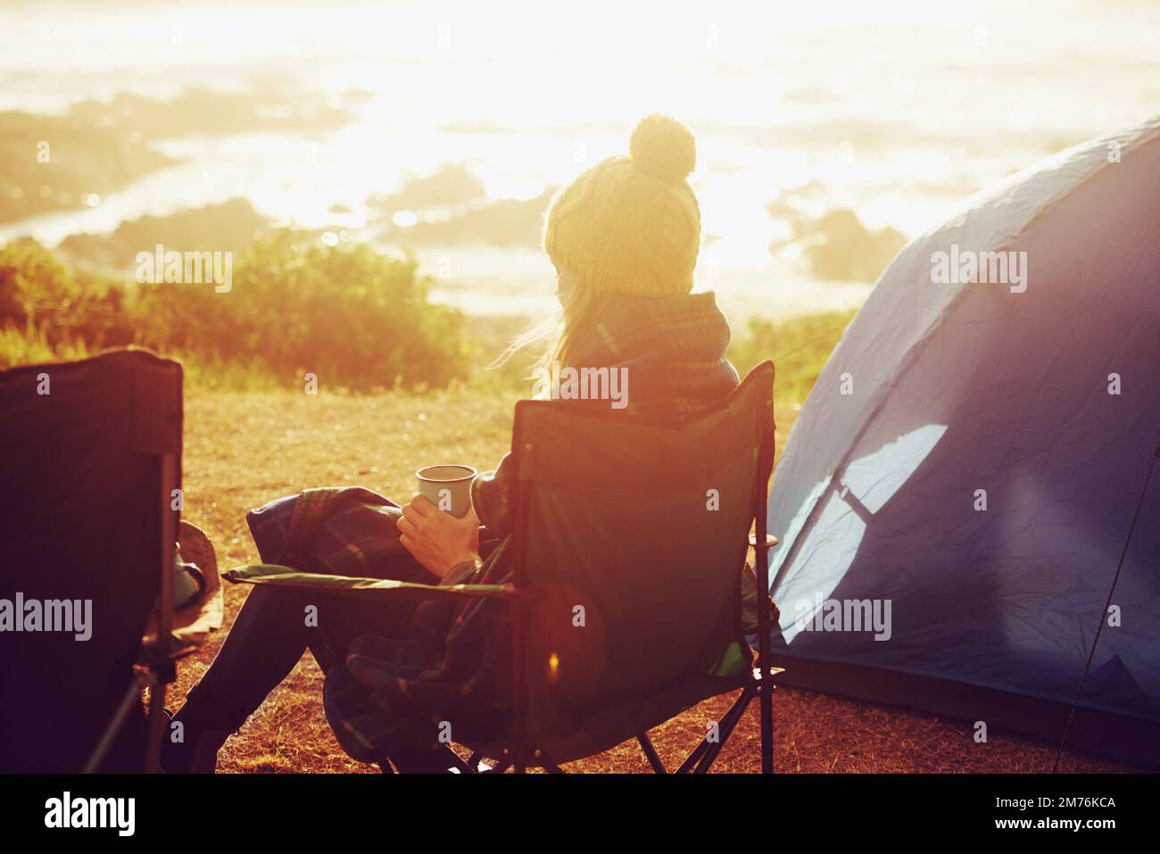 Sweet solitude as the sun rises. Rear view of a young woman sitting in ...