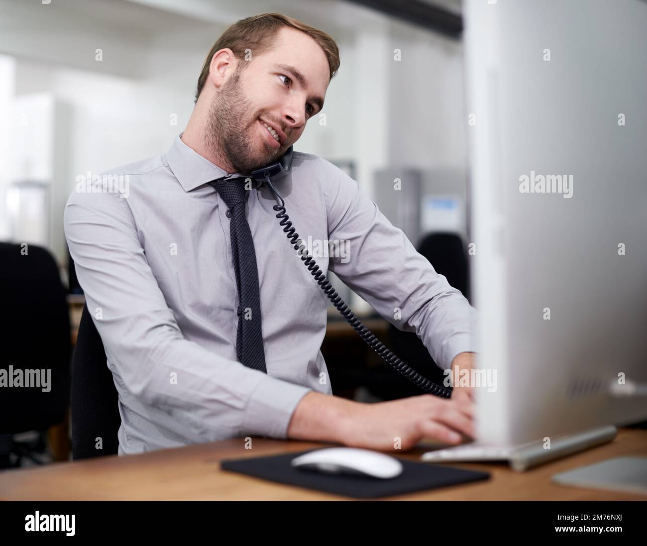 Hes a one man team. a young man using a computer and talking on the ...