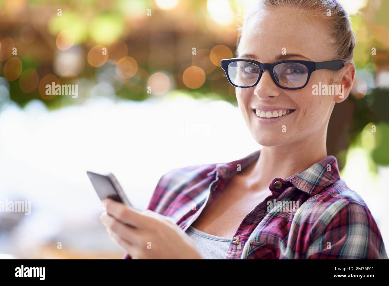 Always in touch. A cropped portrait of a beautiful young woman sitting ...