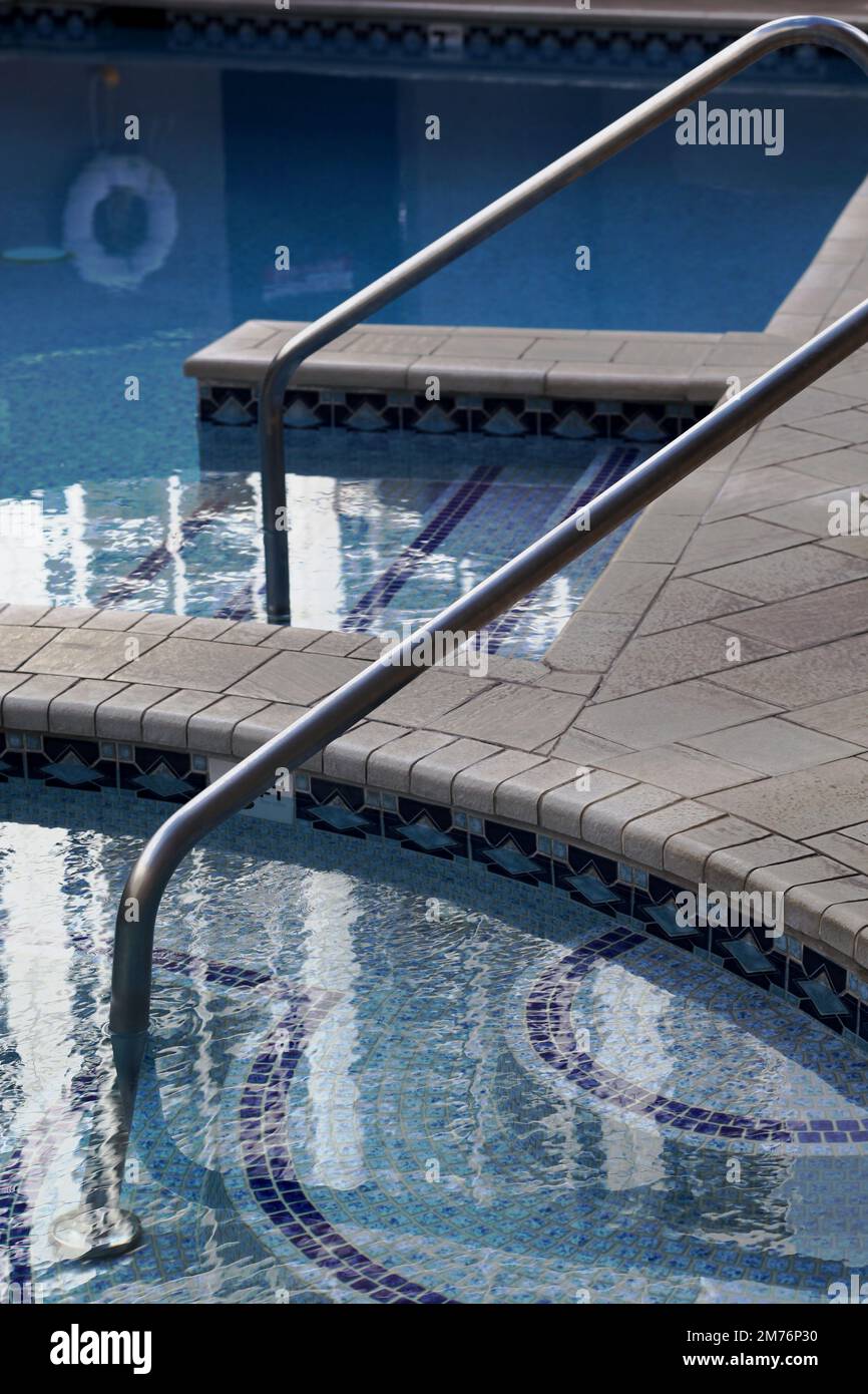 Pool surface reflecting city high rise. Stairs and handrail leading ...
