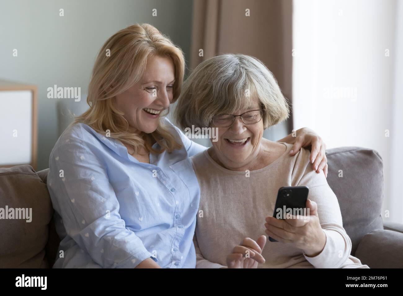 Joyful mature daughter and senior mom sharing mobile phone Stock Photo ...