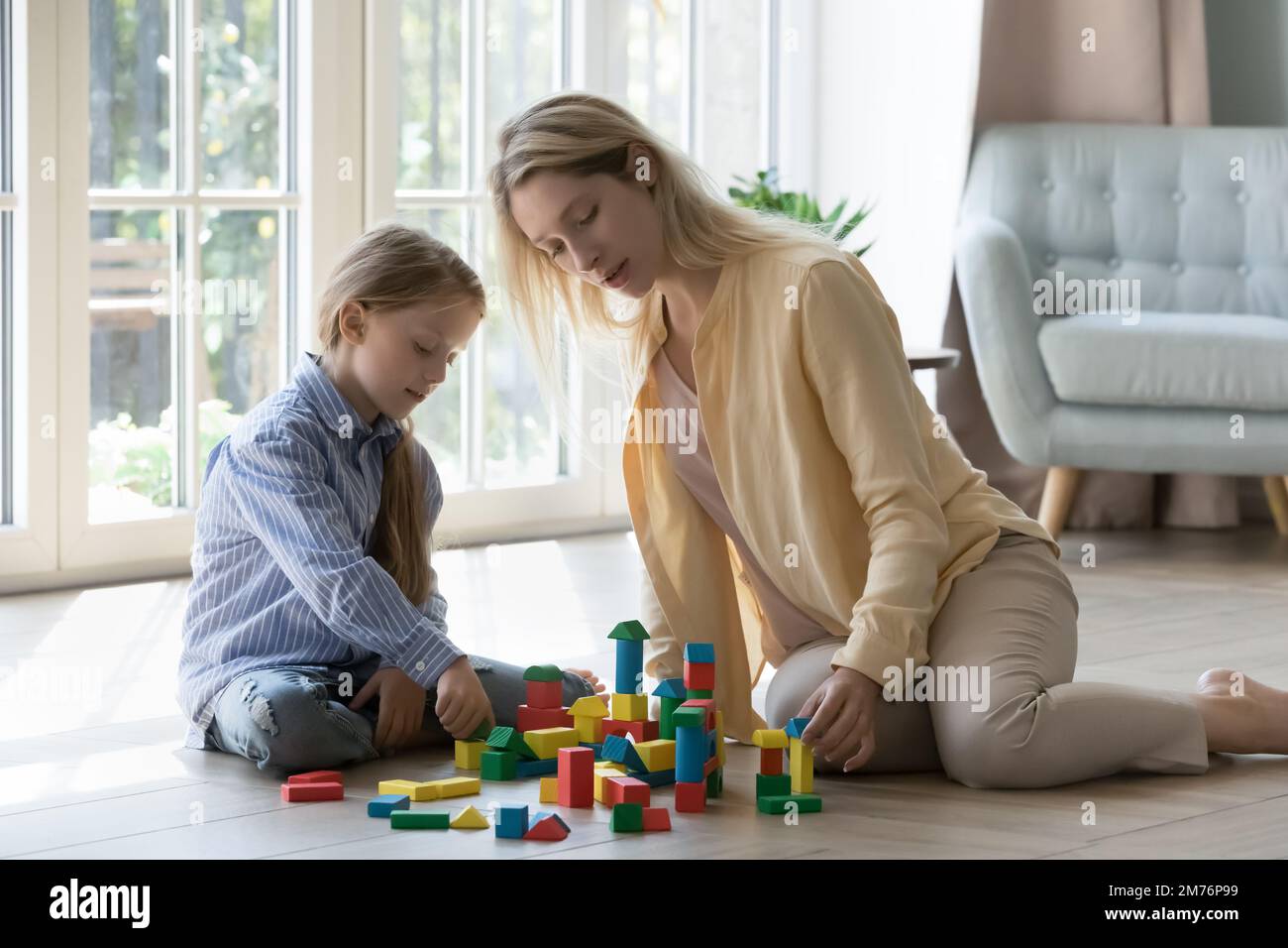 Serious mother and daughter girl stacking toy towers Stock Photo - Alamy