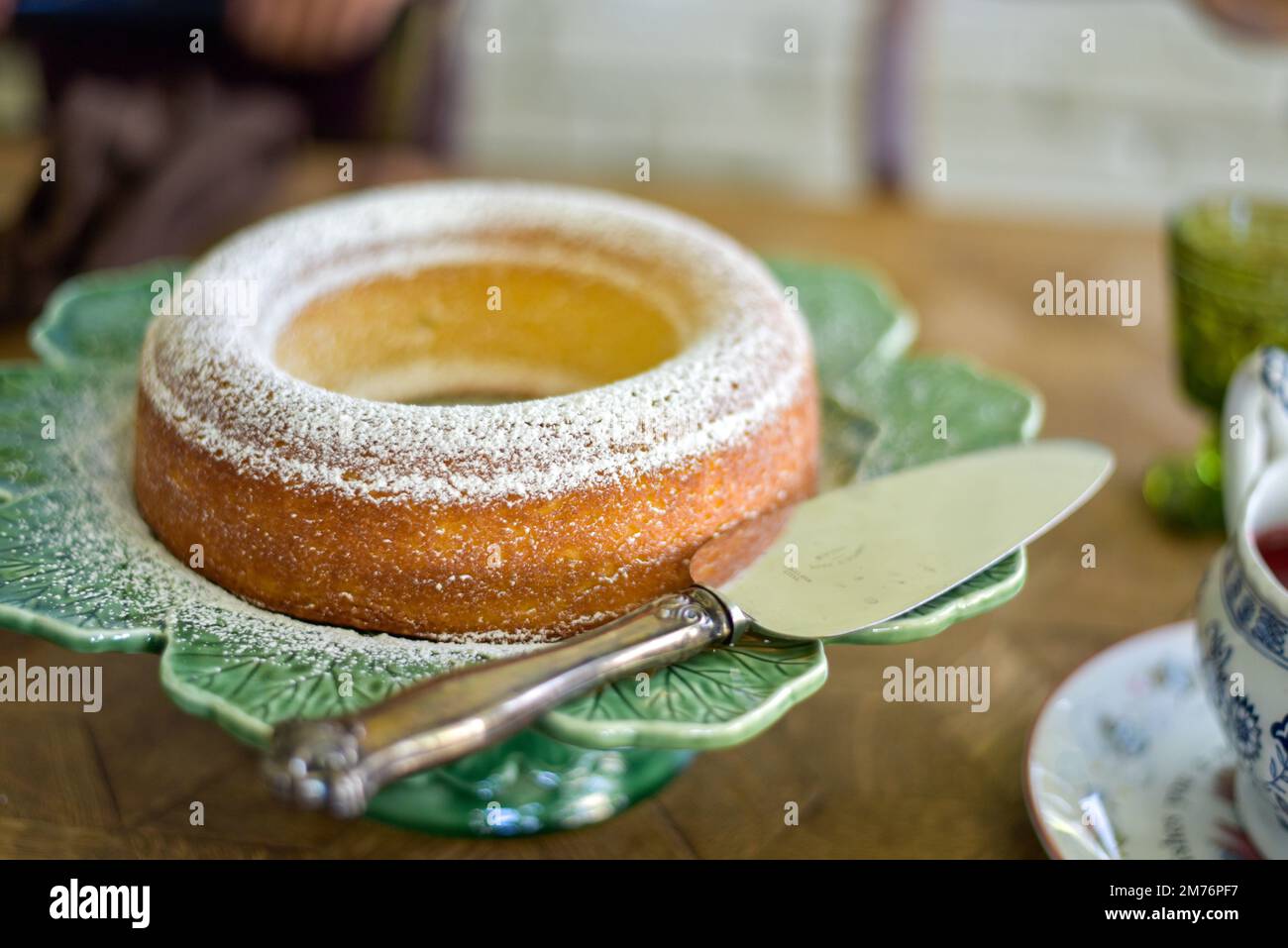 Round sponge cake with a fine dusting of white powered sugar sitting of ...