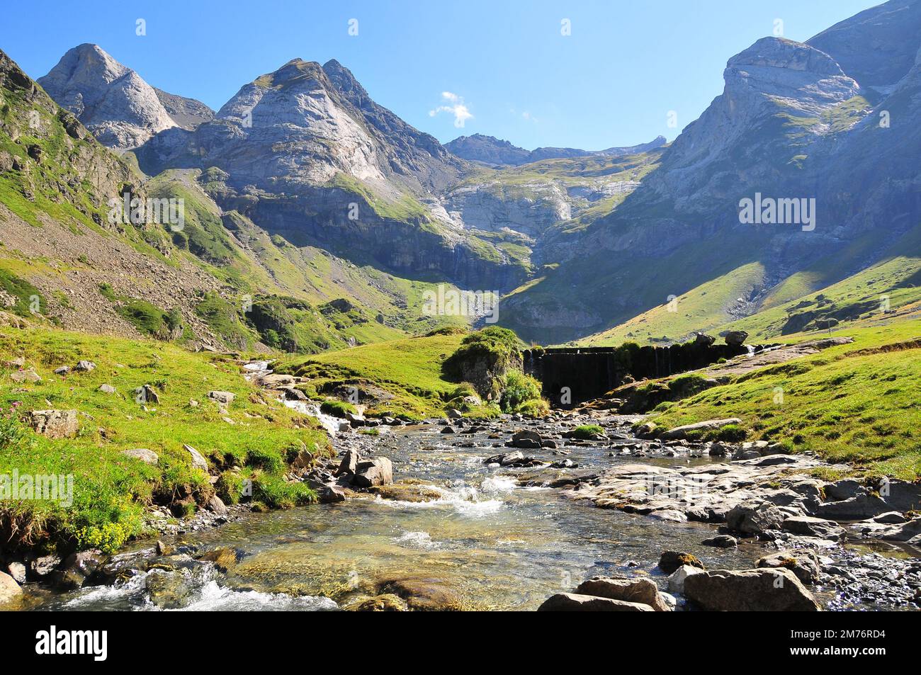 A scenic view of a river flowing through a green valley in mountains on ...