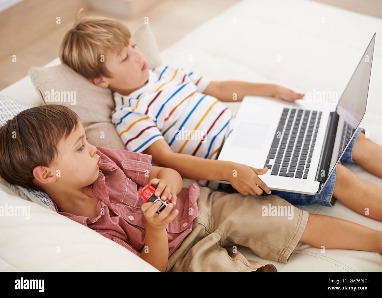 Keeping themselves busy. Two boys watching stories on a laptop Stock ...