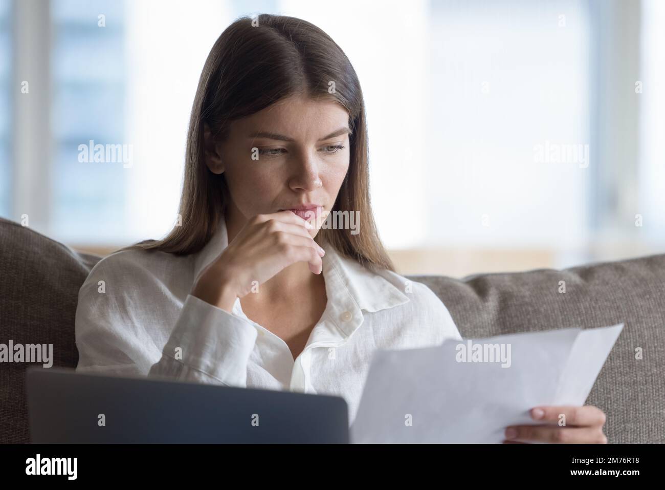 Serious woman sits with laptop read notification from bank Stock Photo ...
