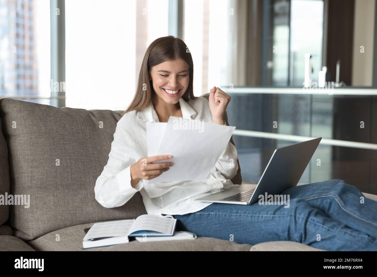 Excited woman sits on sofa read paper notice feels happy Stock Photo ...