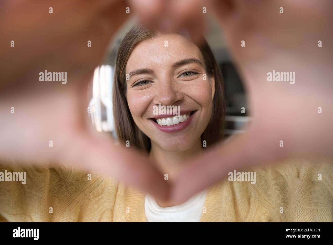 Woman staring at cam through joined fingers showing heart symbol Stock ...