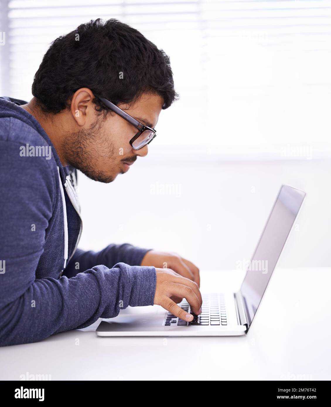 Emmersed in his work. a handsome young man working on his laptop in an ...