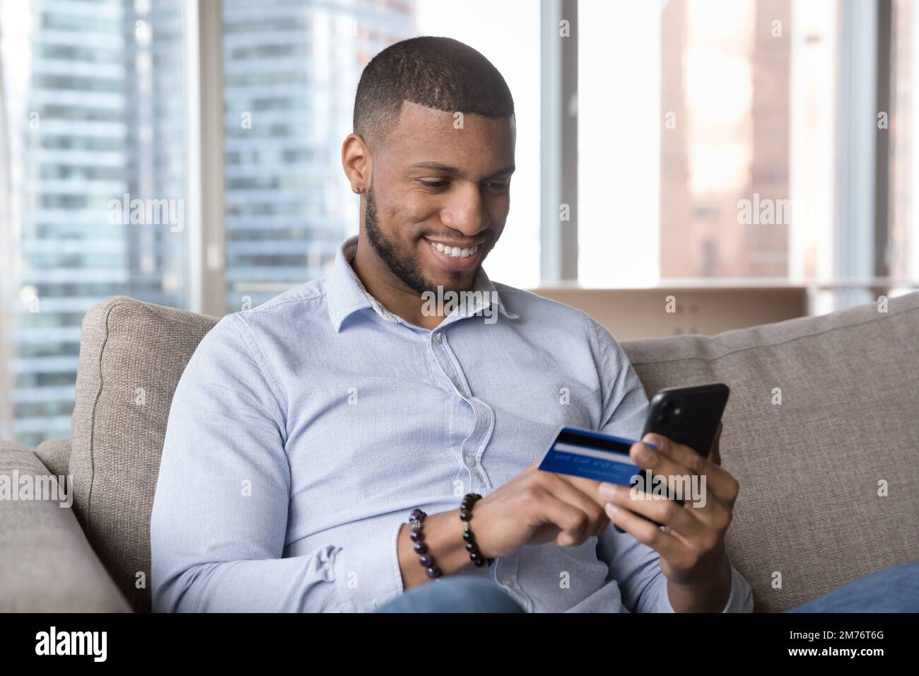 African guy holding card and smartphone, spend money on internet Stock ...
