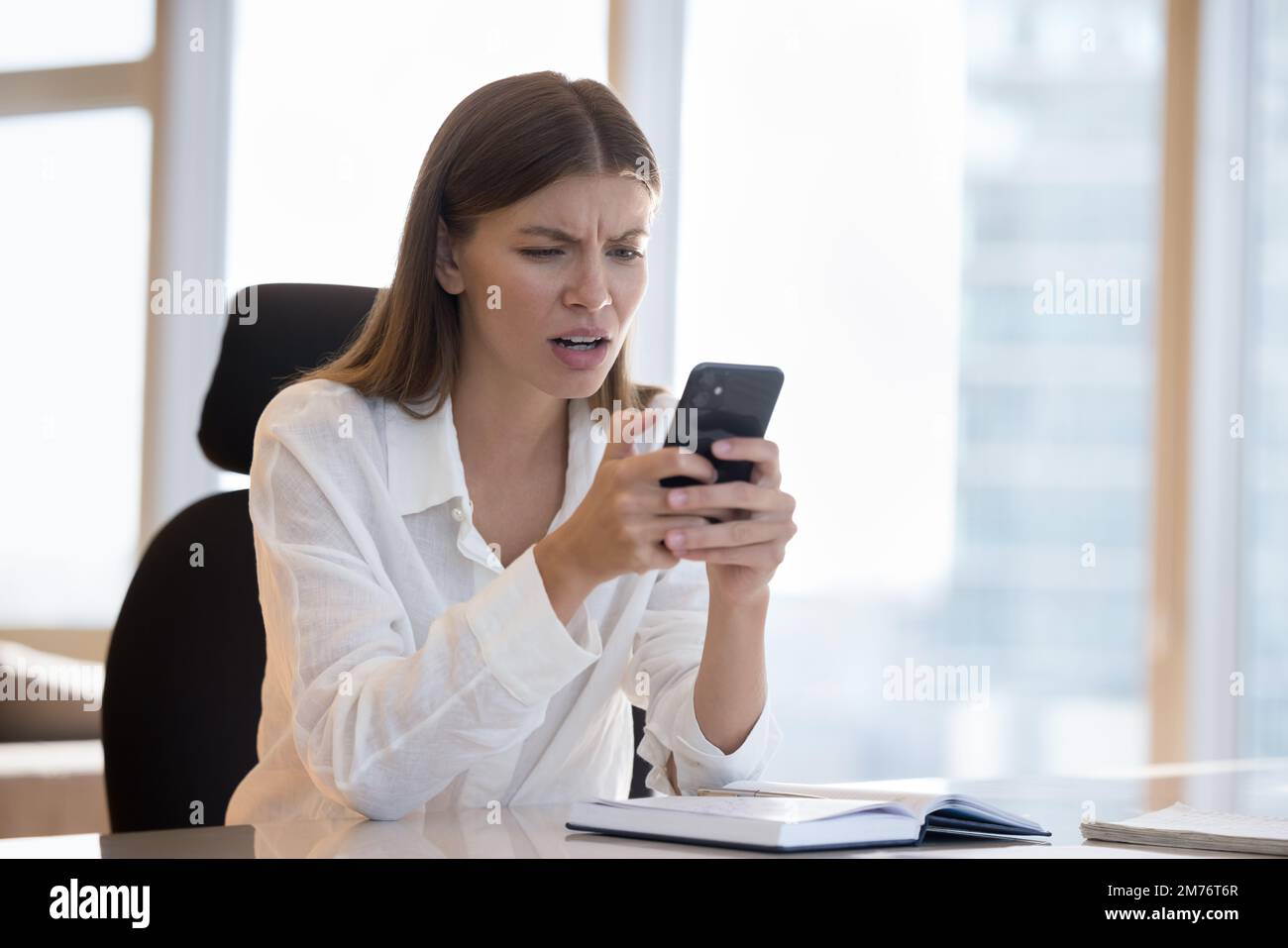 Young female staring at smart phone screen read awful sms Stock Photo ...