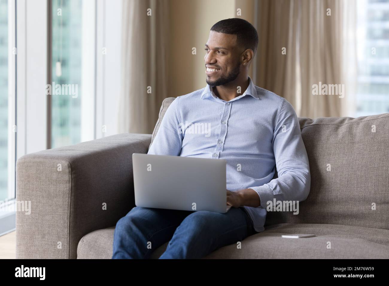 African man resting on couch with wireless computer on laps Stock Photo ...