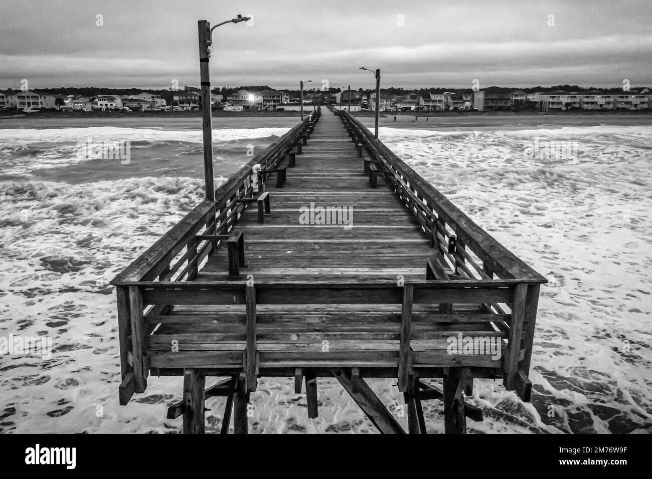A high angle shot of a wooden pier on sea waves crashing against the ...