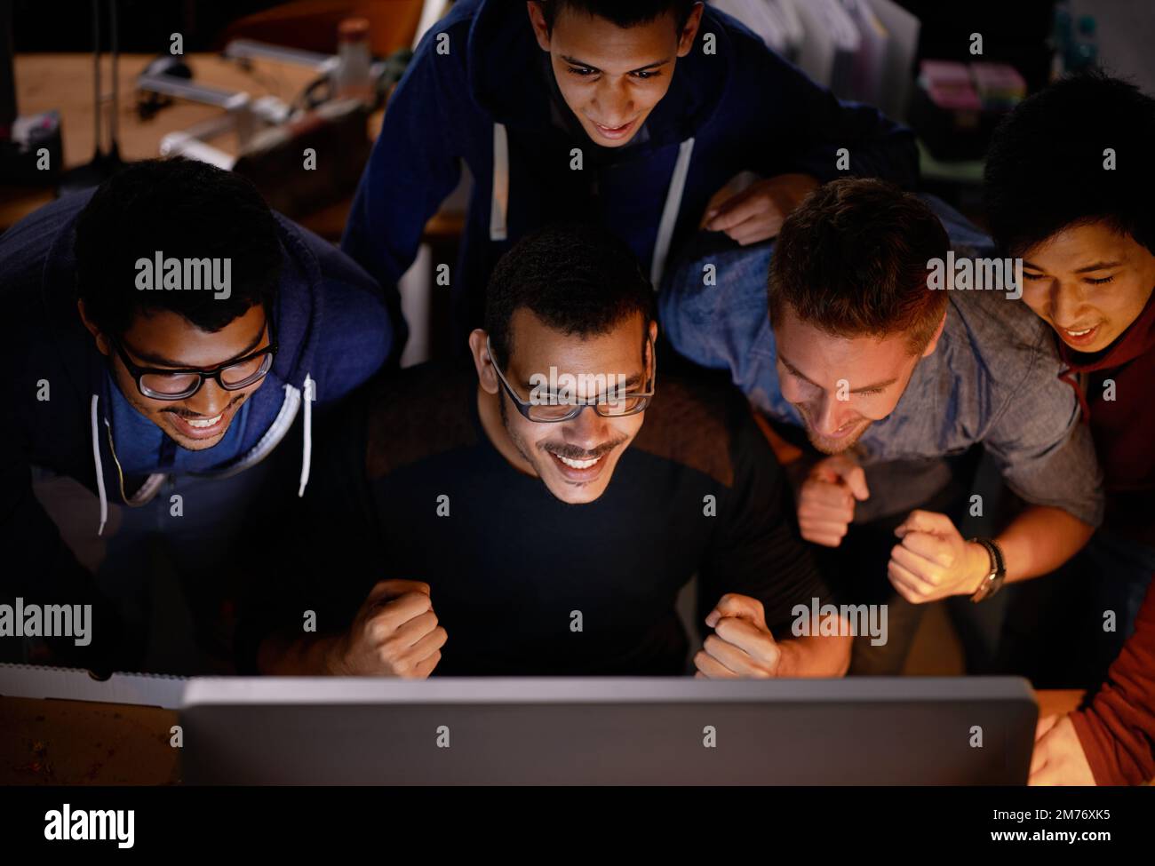 Getting behind the team. a group of young man cheering at a monitor in ...