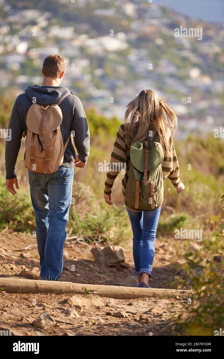 Doing it side by side. Rear view shot of a young couple walking down a ...