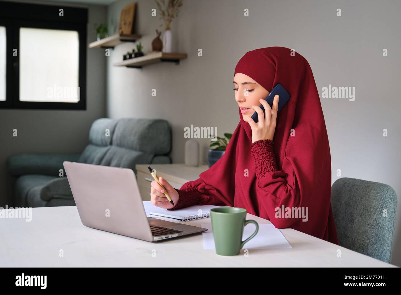Muslim young woman student in hijab in a phone call while studying at ...