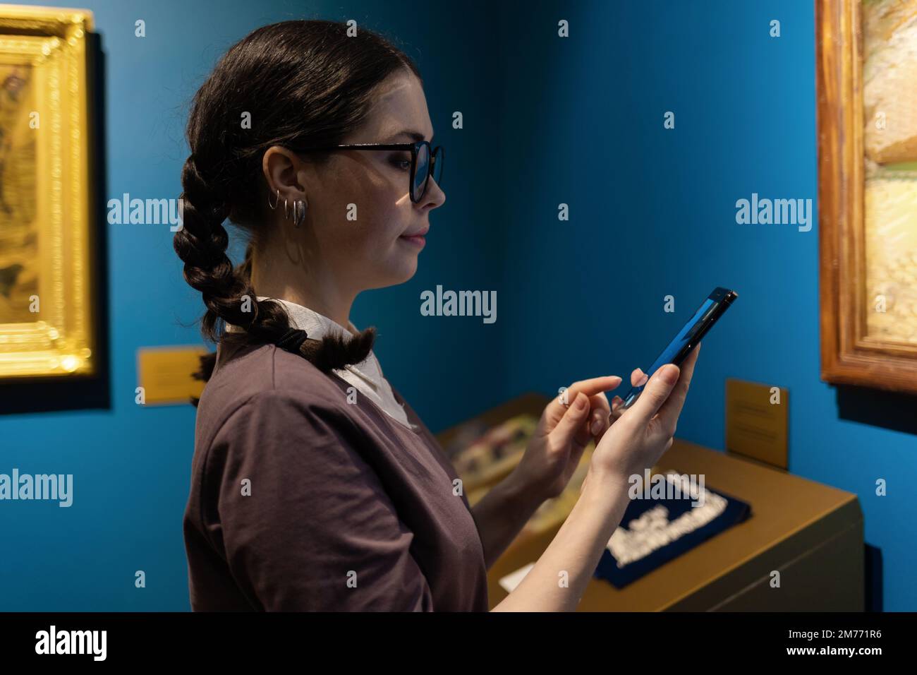 Modern museum exhibition. Side view of young Caucasian woman uses ...