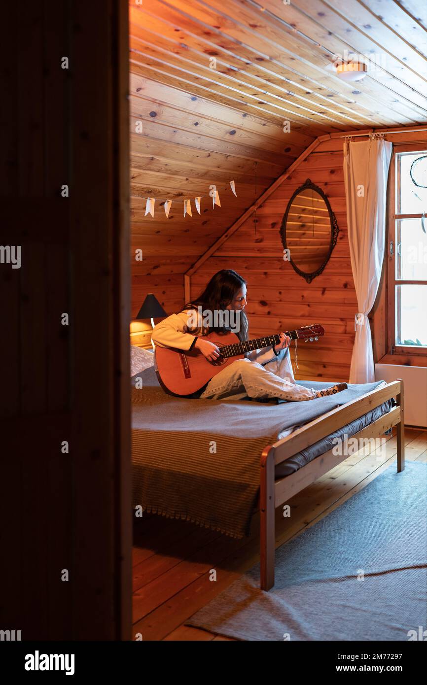 Young woman songwriter or composer sitting in cozy attic bedroom ...