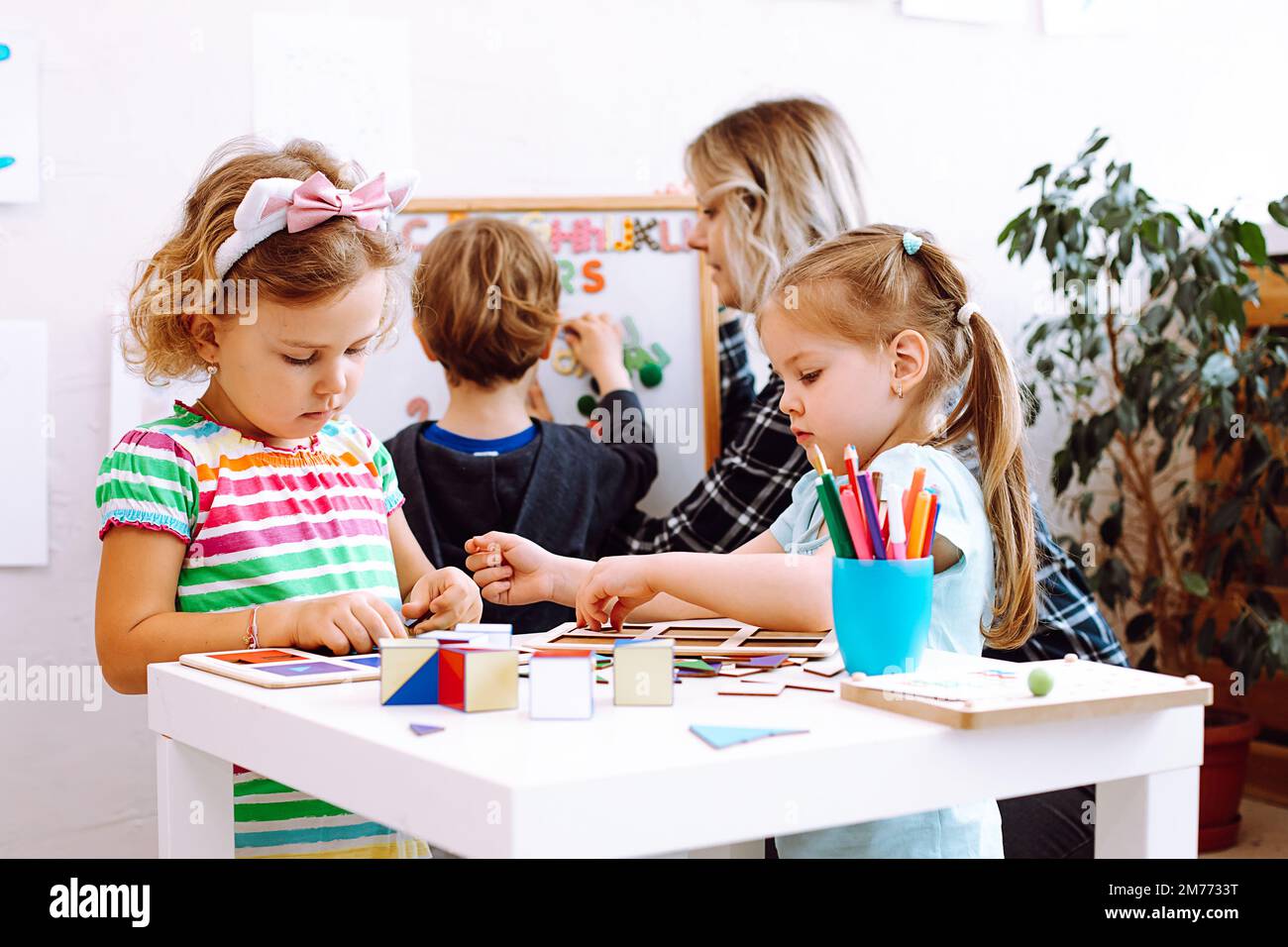 Cute little girls with interest fold geometric figures on desk in ...
