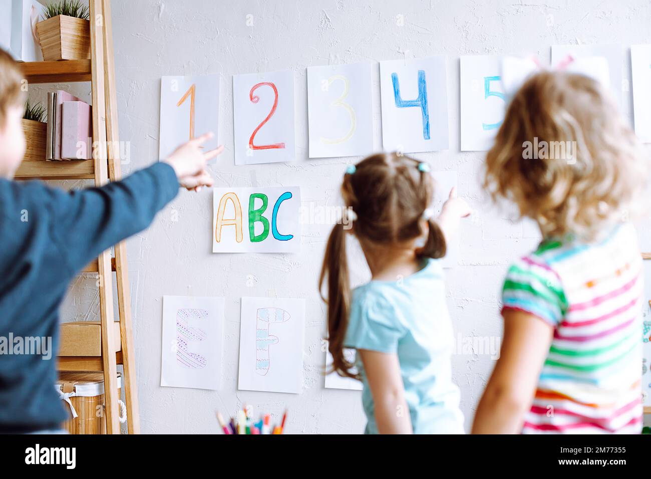 Children stand with back and learn english letters, alphabet and ...