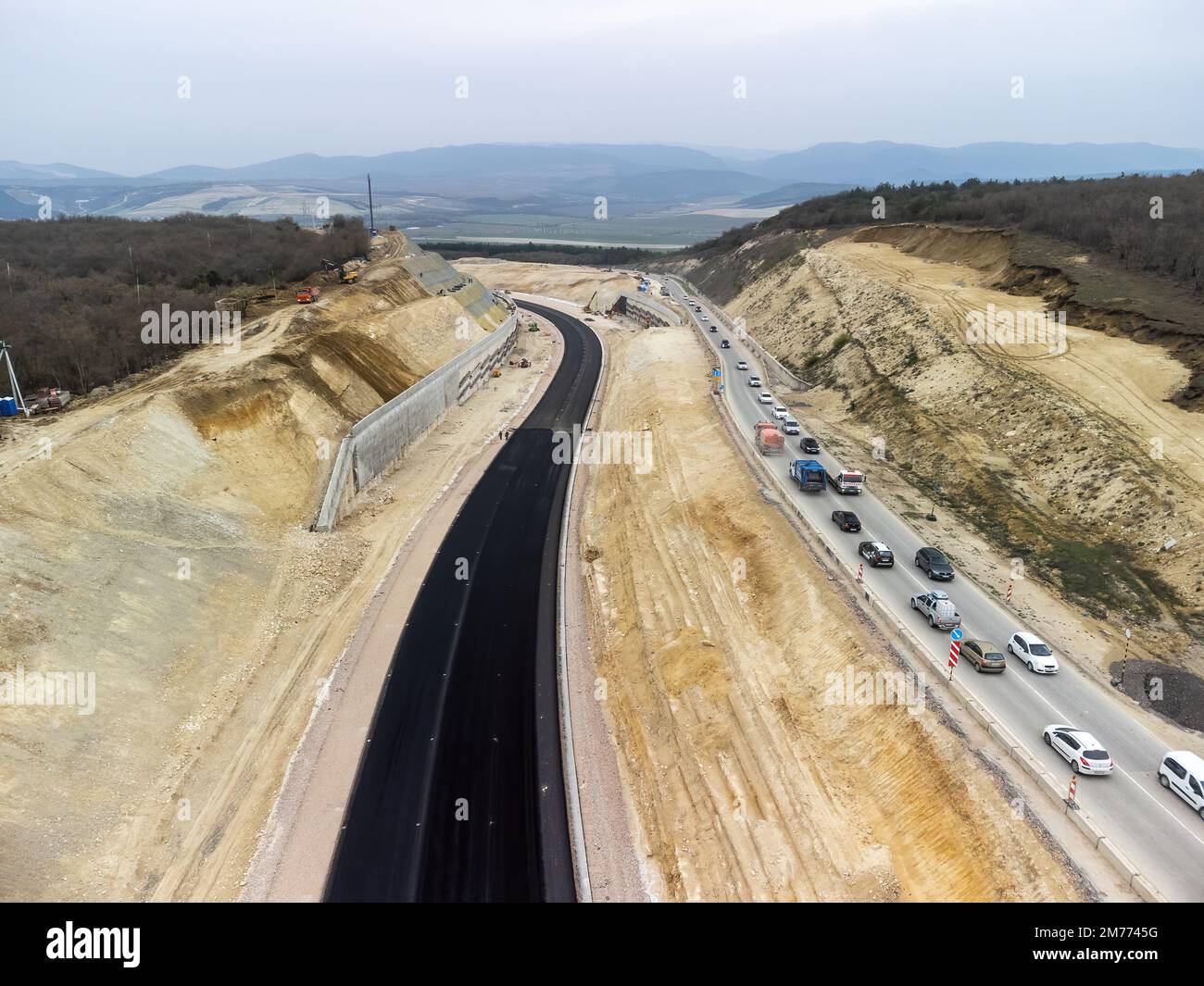 Mountain road constraction. Workers reinforce the slope over the new ...