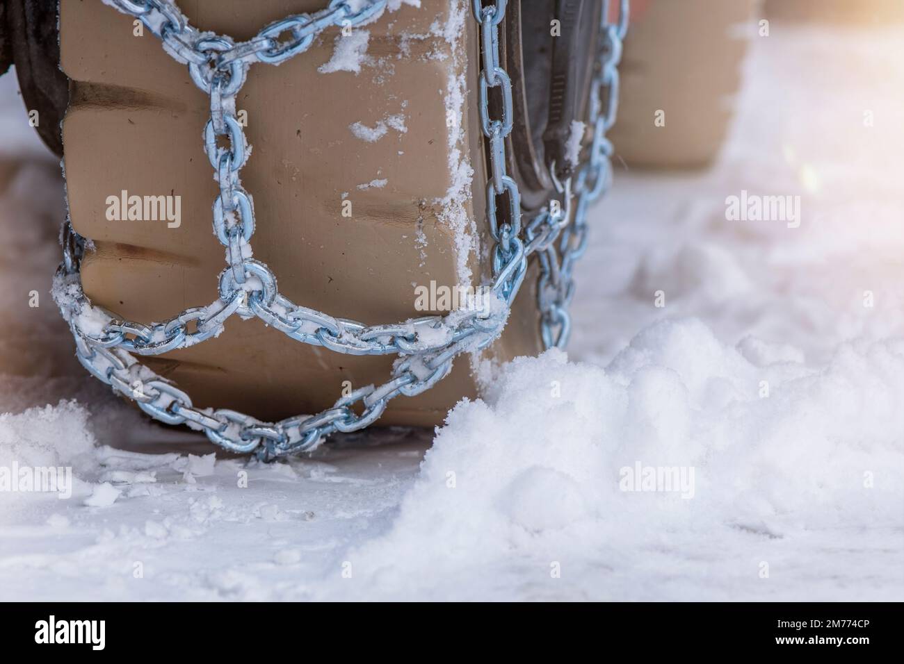 Wheel in the snow with safety and anti-skid chains. Loader or tractor ...